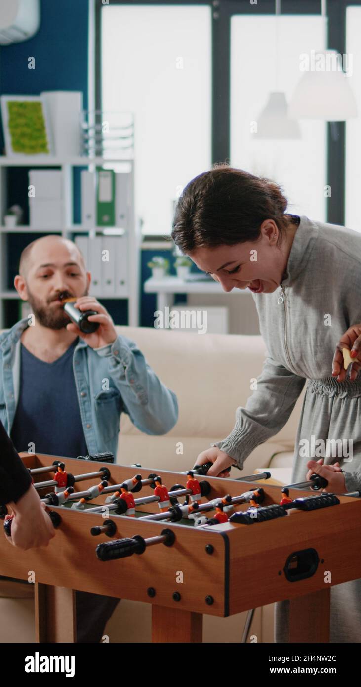 Multi ethnic coworkers playing foosball game at table for entertainment ...
