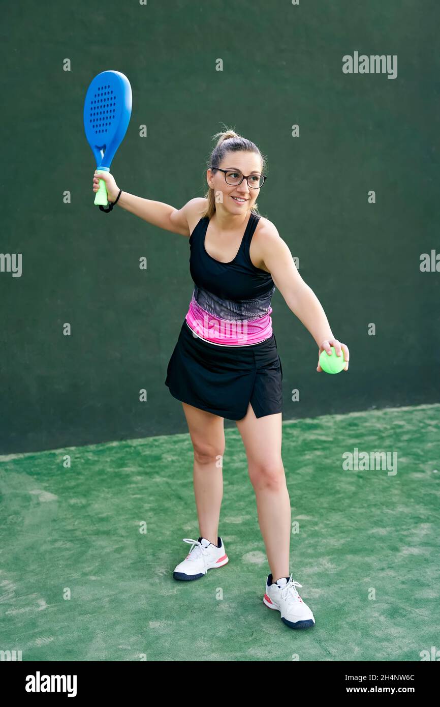Female athlete preparing to shoot ball with racket during padel patch ...