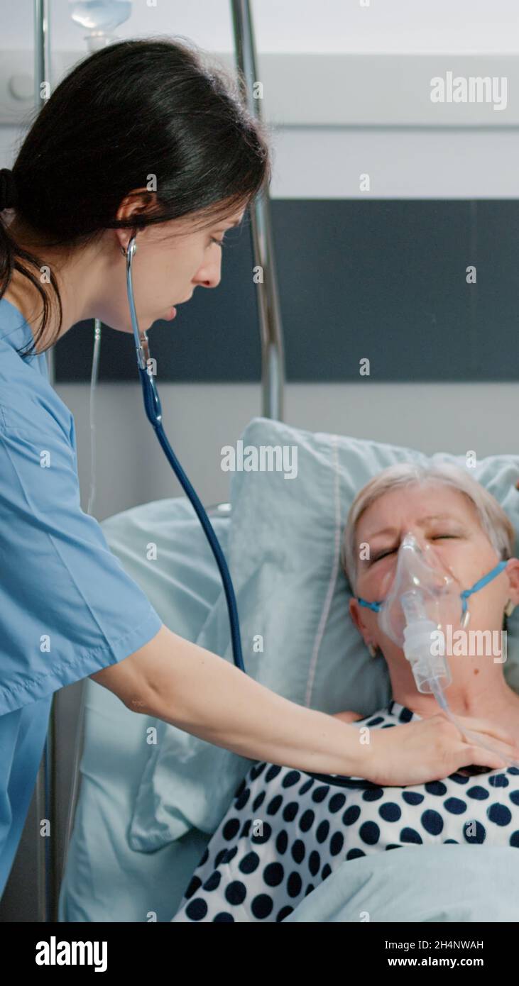 Doctor and nurse using oxygen tube mask for aged patient with heavy ...