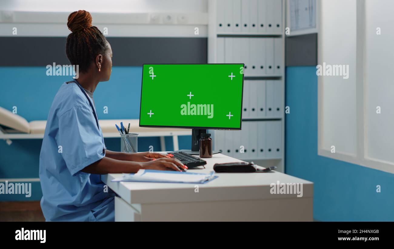 Medical assistant using horizontal green screen on computer in cabinet ...