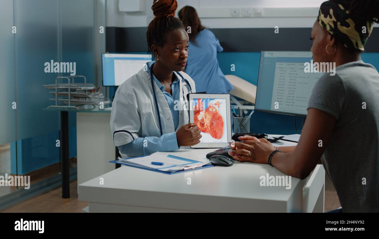 Doctor showing tablet with heart figure for cardiology checkup to ...