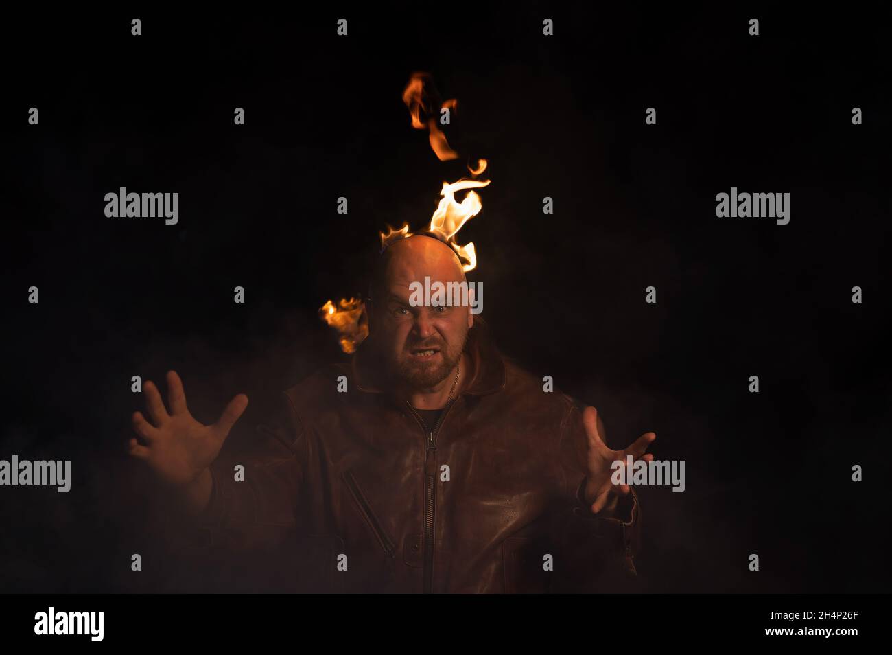 Bald man in a leather jacket with a burning head on a dark background ...