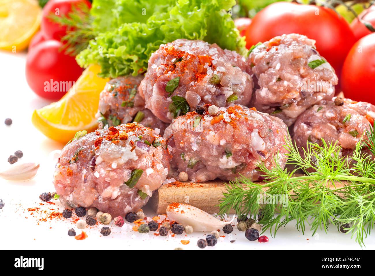 Fresh meatballs with various vegetables on a white background ...