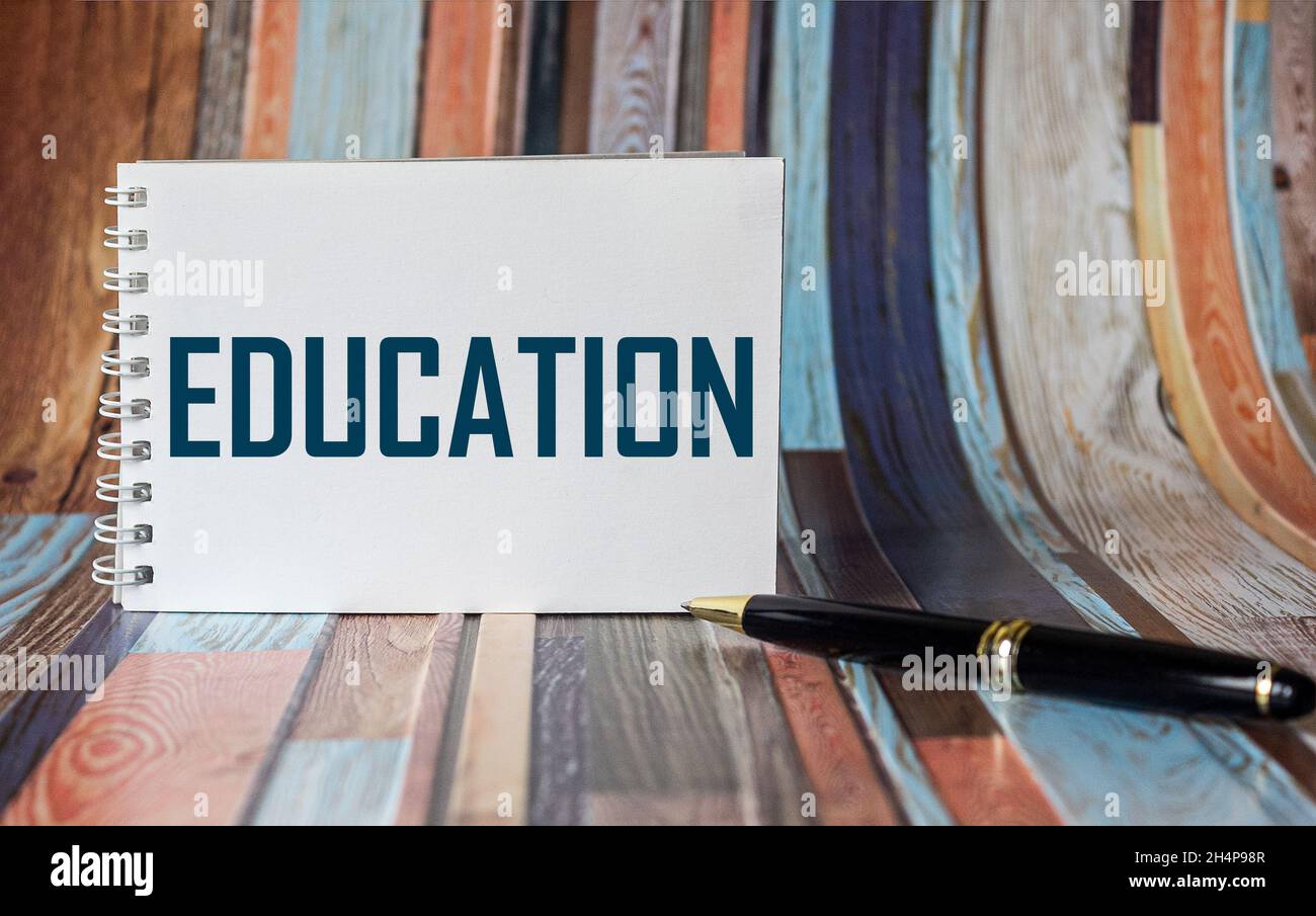 The word EDUCATION is written on a notepad and on a striped background ...