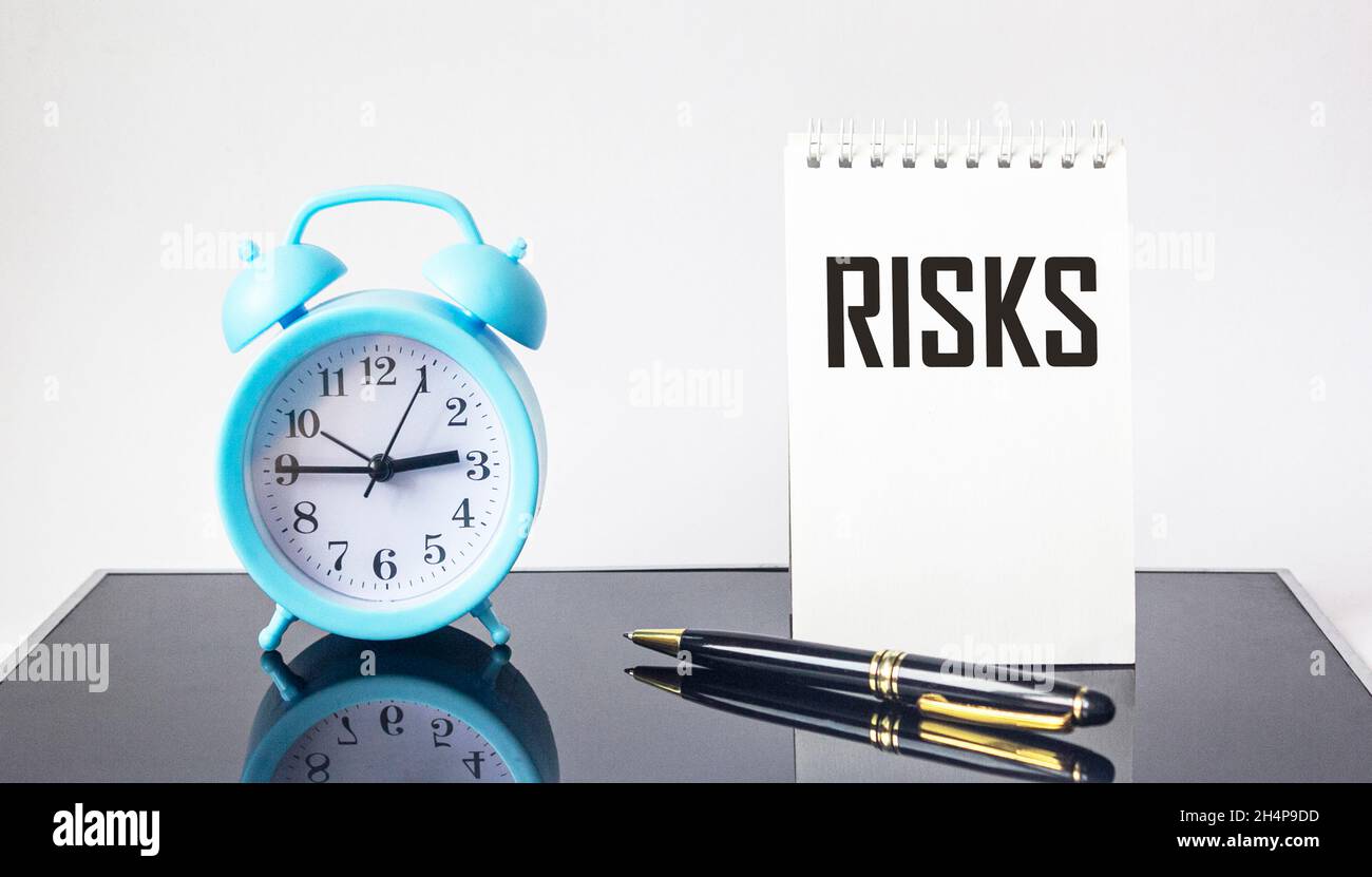 Notepad with the text Risks on a black mirrored background and a white ...