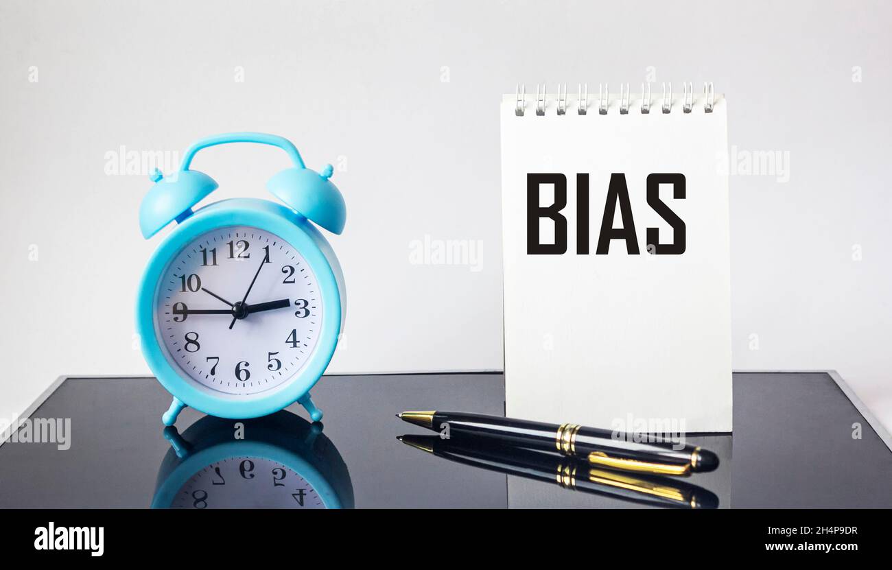 There is an alarm clock on a black mirrored background, a pen and a ...