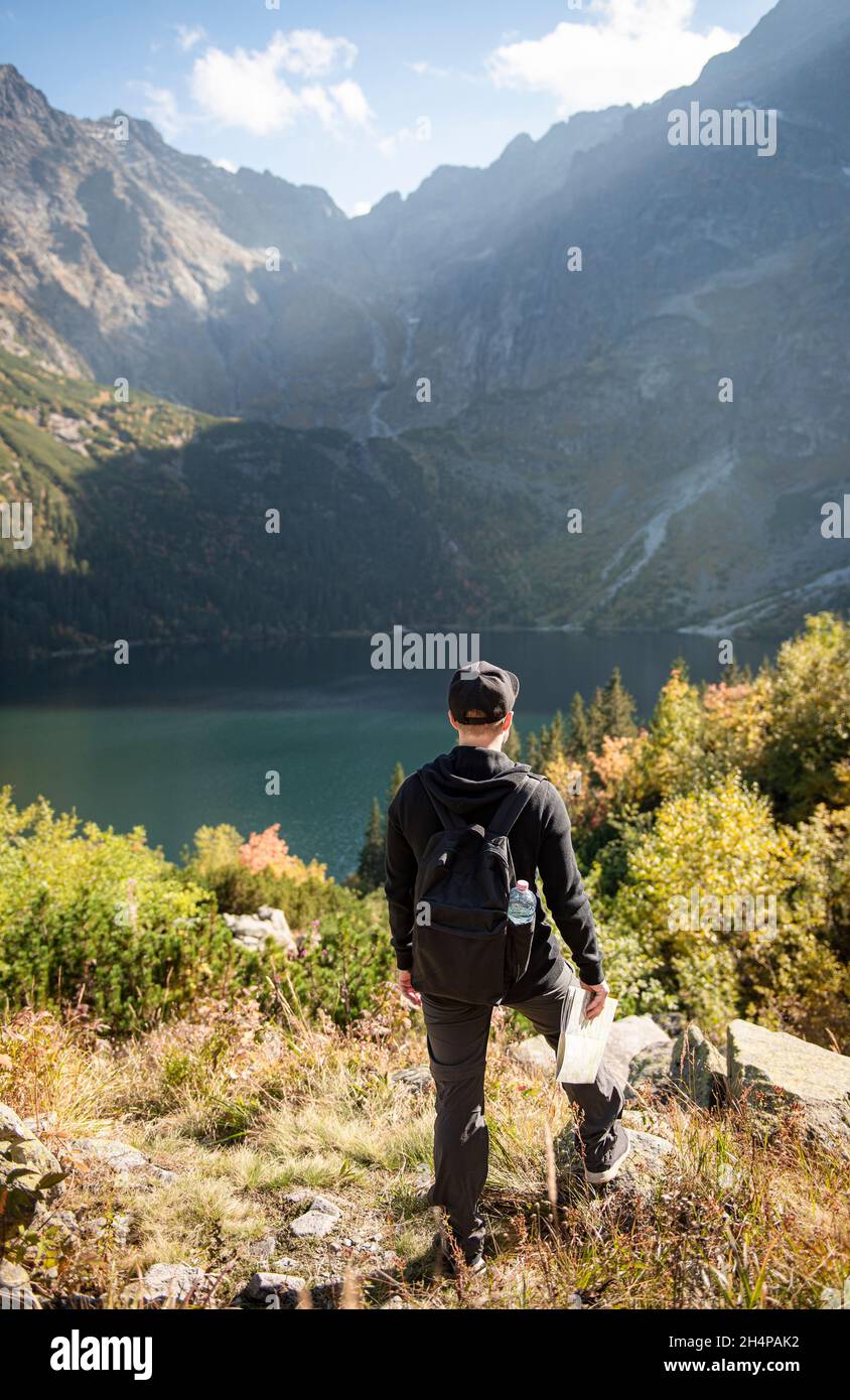 Young man traveler with map and backpack relaxing outdoor with rocky ...