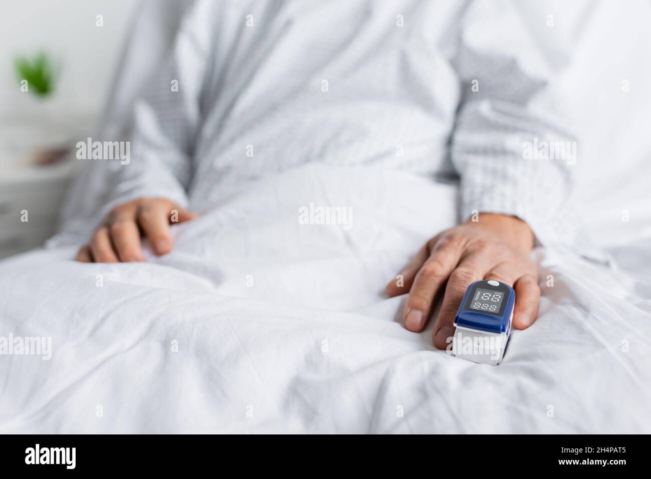 Cropped view of pulse oximeter on hand of blurred elderly patient on ...