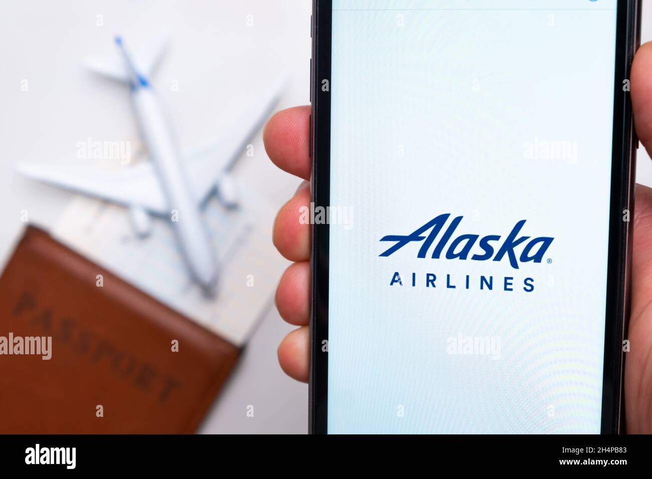Alaska airlines company logo on the screen of mobile phone in man hand ...