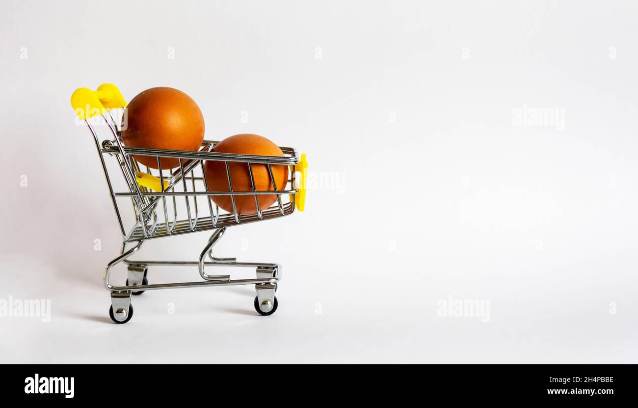 Two chicken eggs in a small shopping cart. Mini cart with eggs on a ...