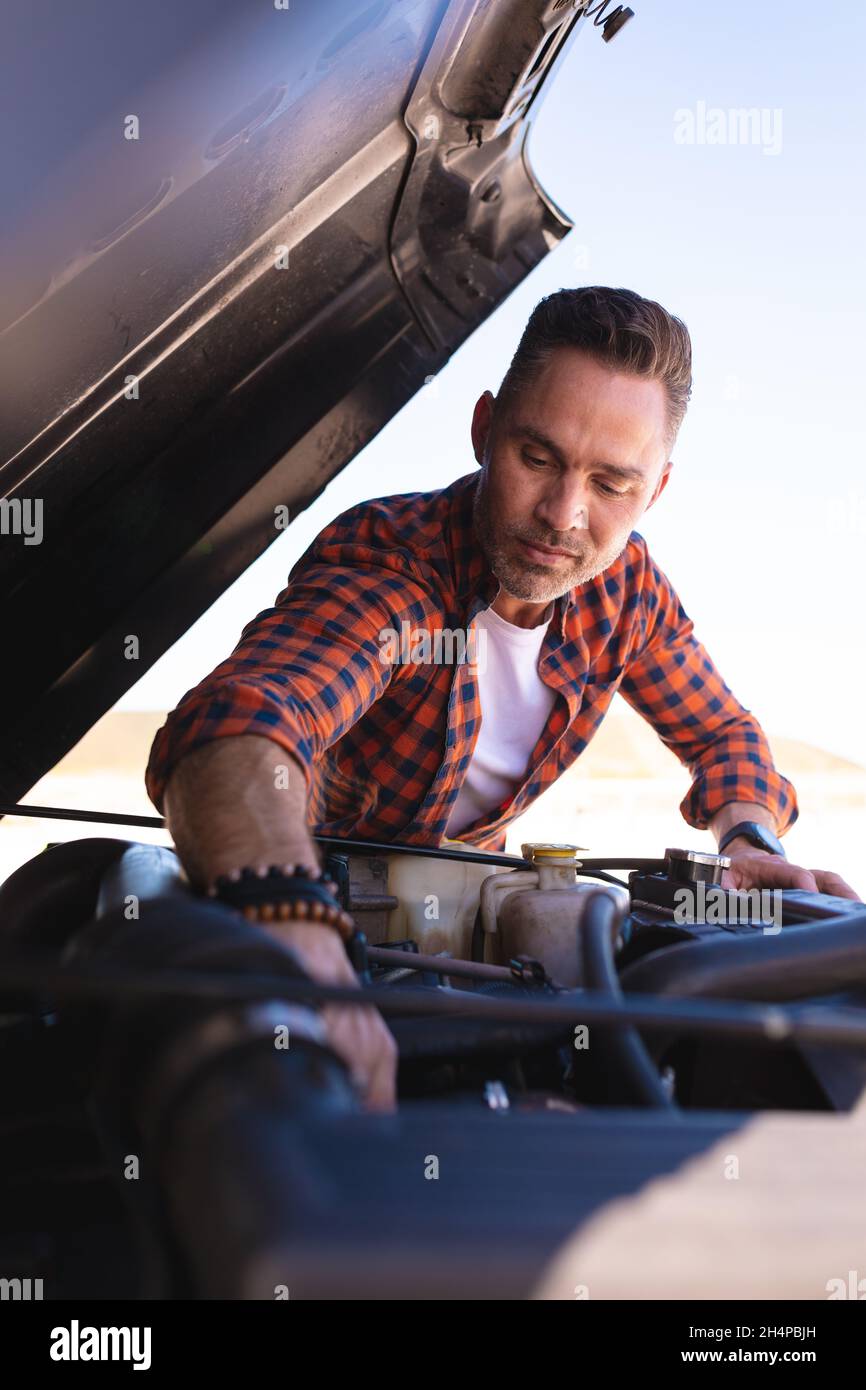 Focused caucasian man repairing car with bonnet open at seaside Stock ...