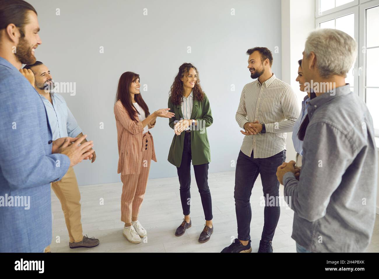 Group of young and mature business people standing and talking during ...