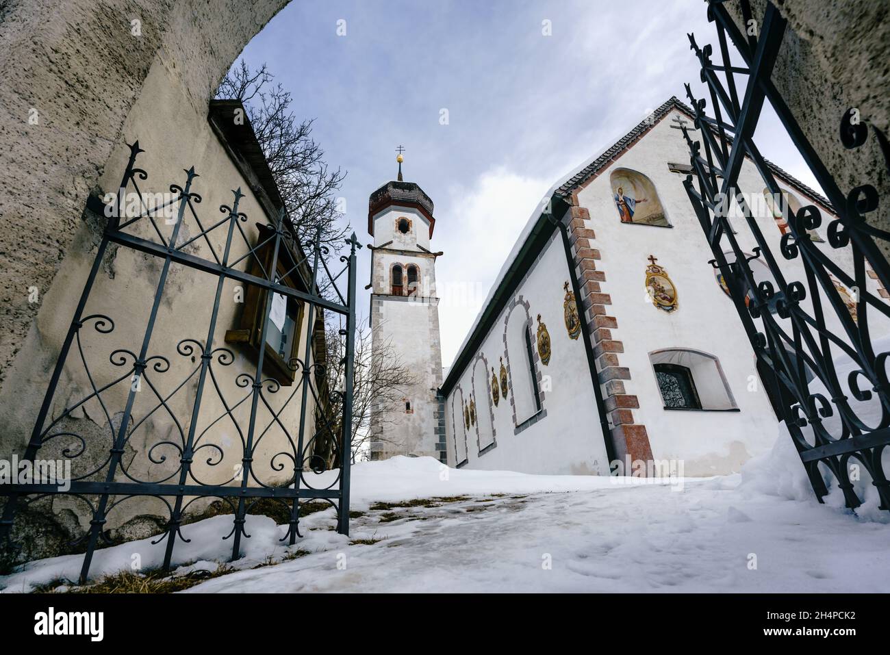 Arch gate to small Austrian church with onion dome in winter landscape ...