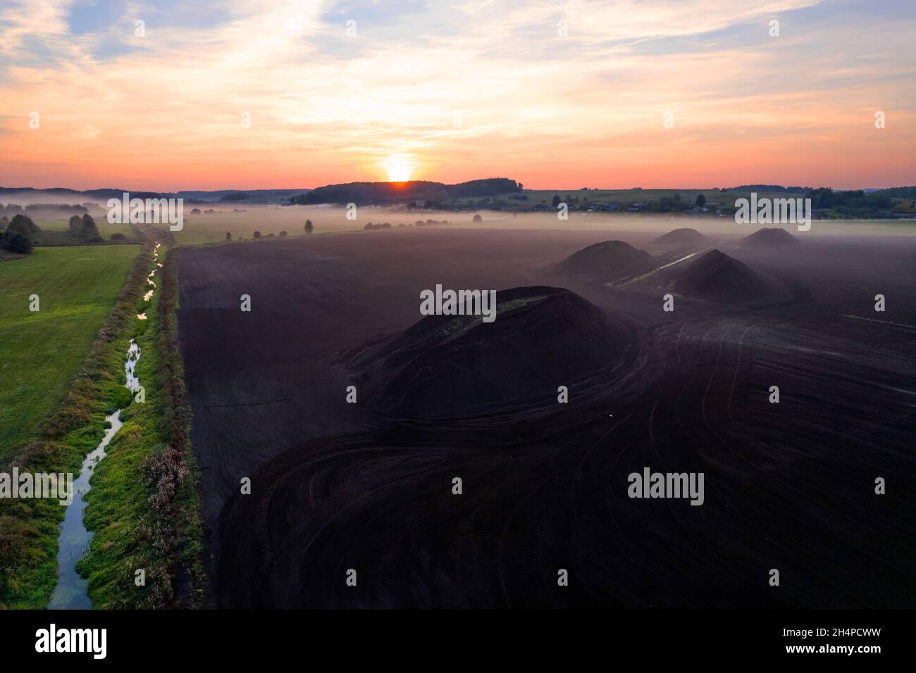 Peat extraction site in fog on sunset. Collecting peat on peatlands ...