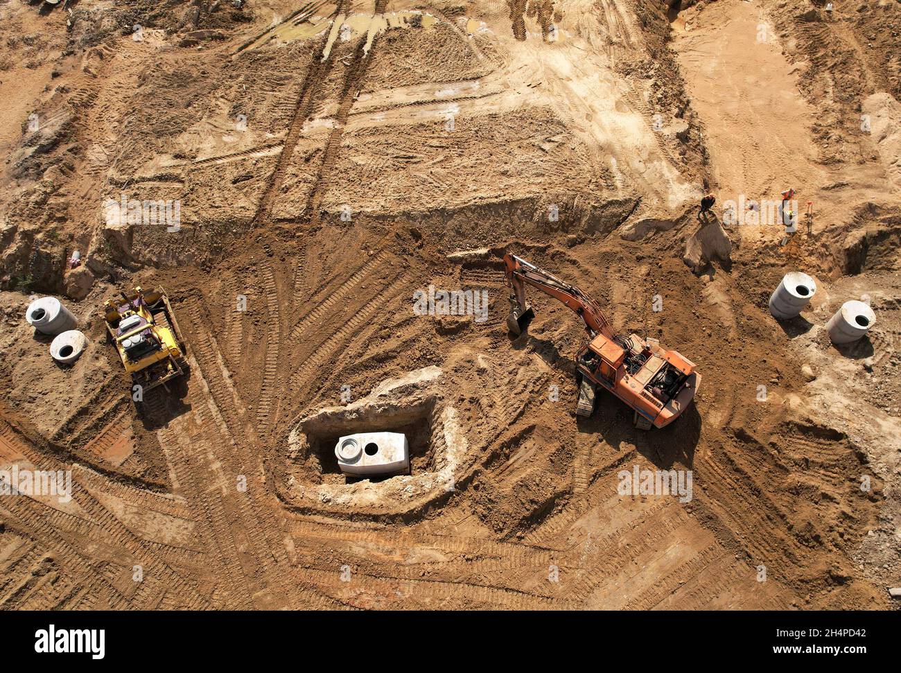 Laying a concrete well ring and sewer pipe at construction site ...