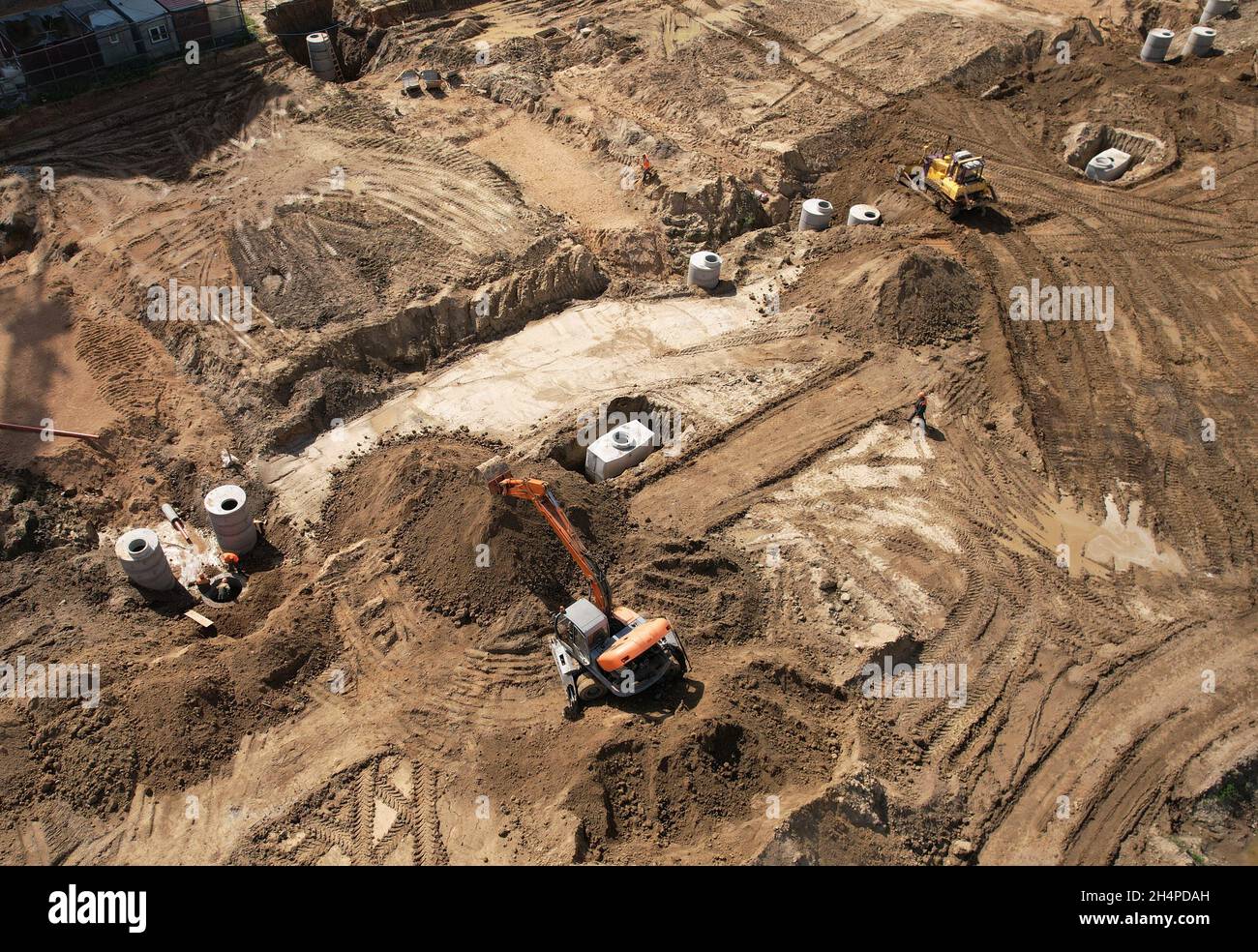 Laying a concrete well ring and sewer pipe at construction site ...