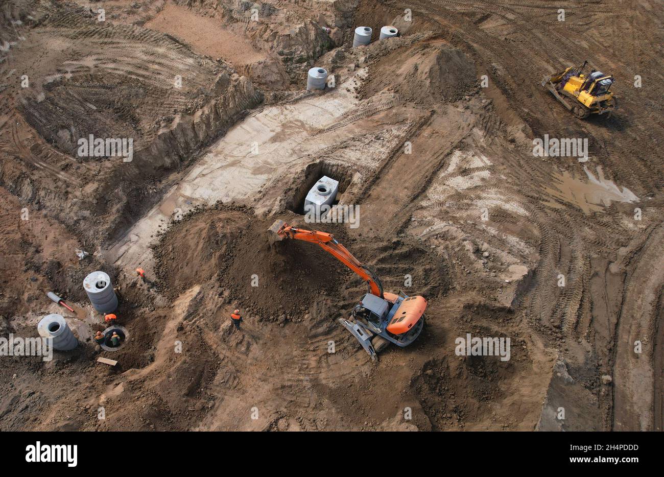 Laying a concrete well ring and sewer pipe at construction site ...