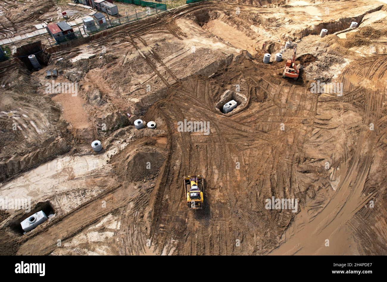 Laying a concrete well ring and sewer pipe at construction site ...
