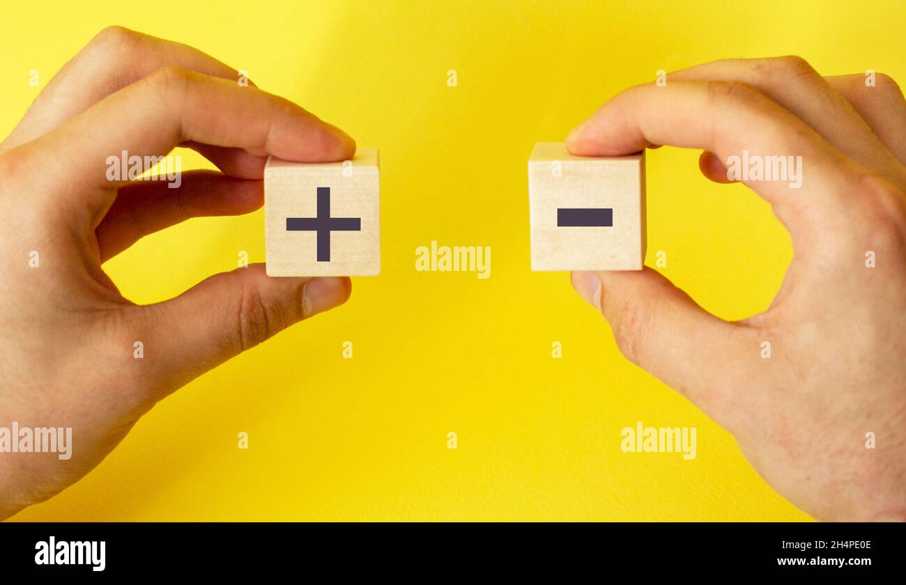blocks in hands on a yellow background with plus and minus Stock Photo ...