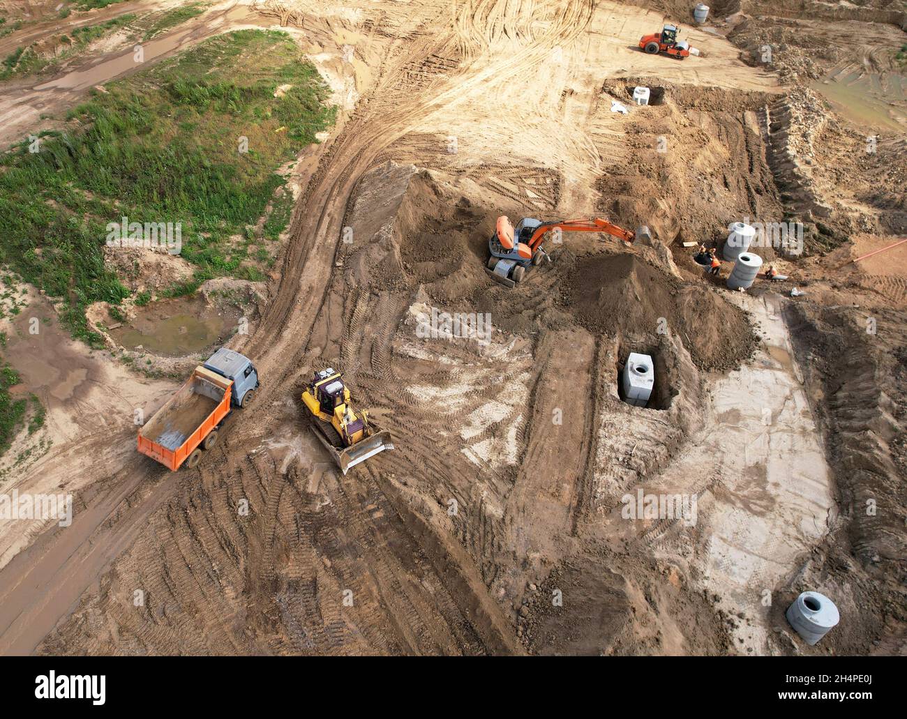 Laying a concrete well ring and sewer pipe at construction site ...