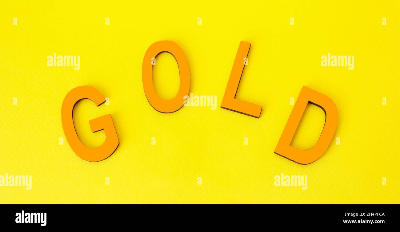 Wooden letters forming the word GOLD on a yellow background. Wealth ...