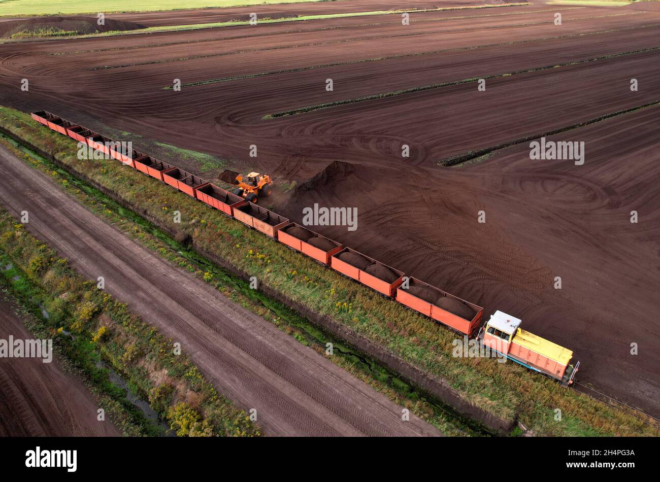 Wheel loader loads peat in freight cars. Aerial view of diesel ...