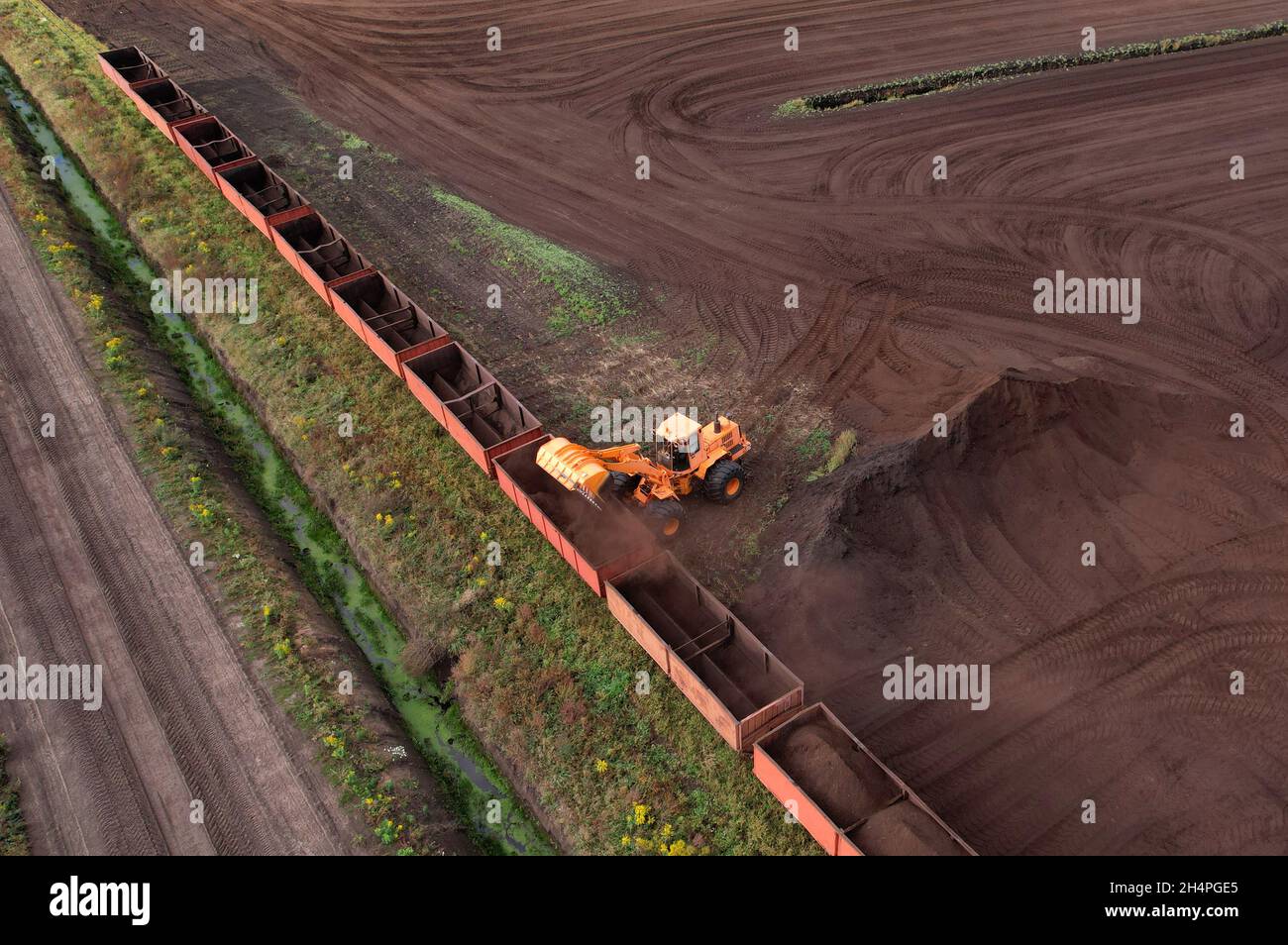 Wheel loader loads peat in freight cars. Aerial view of diesel ...
