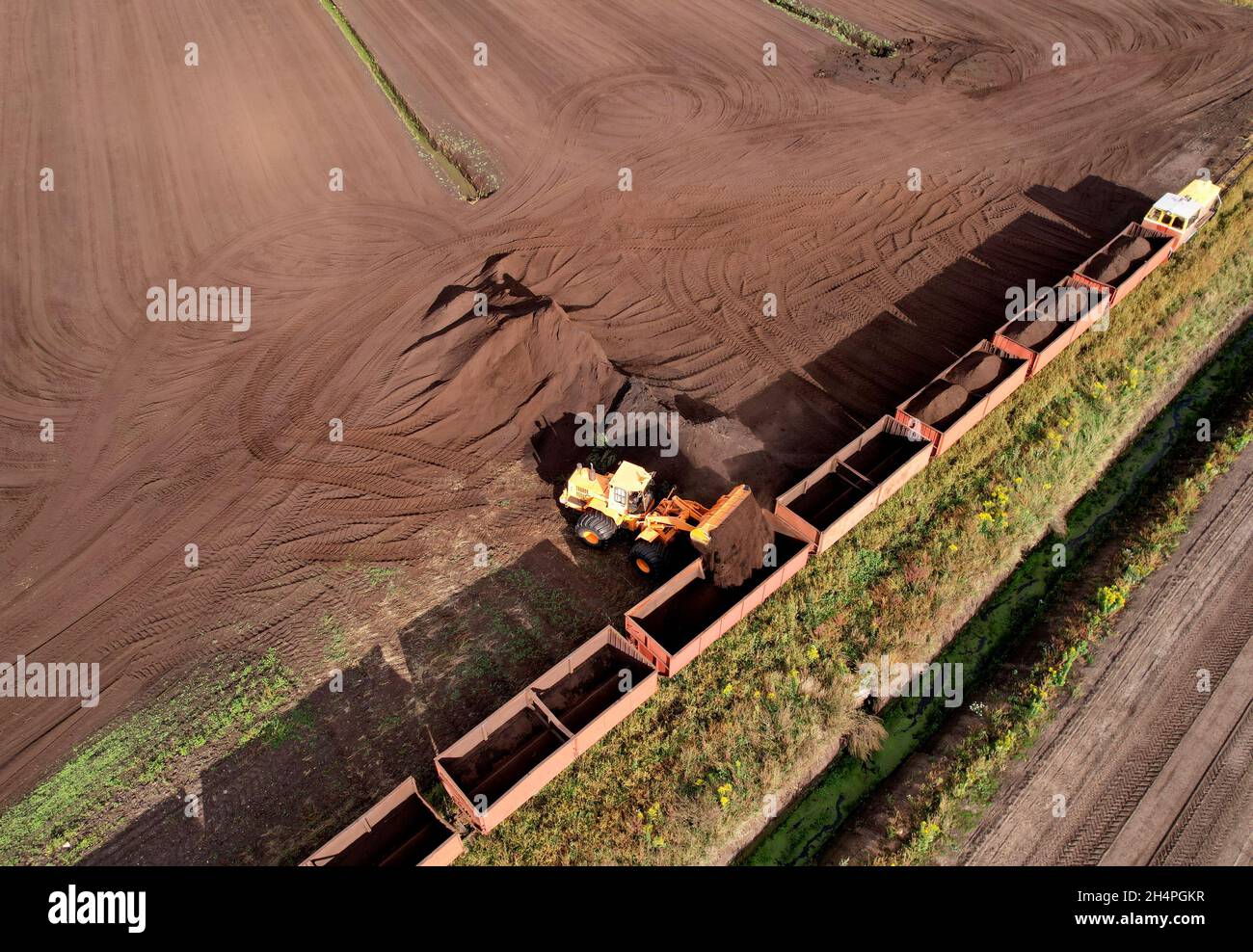 Wheel loader loads peat in freight cars. Aerial view of diesel ...