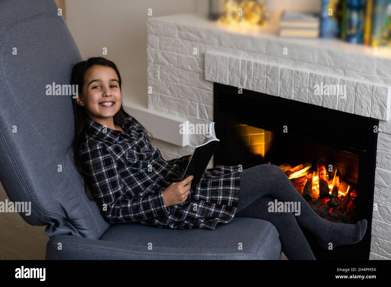 little cute girl sitting n and reading book. Cozy interior Stock Photo ...