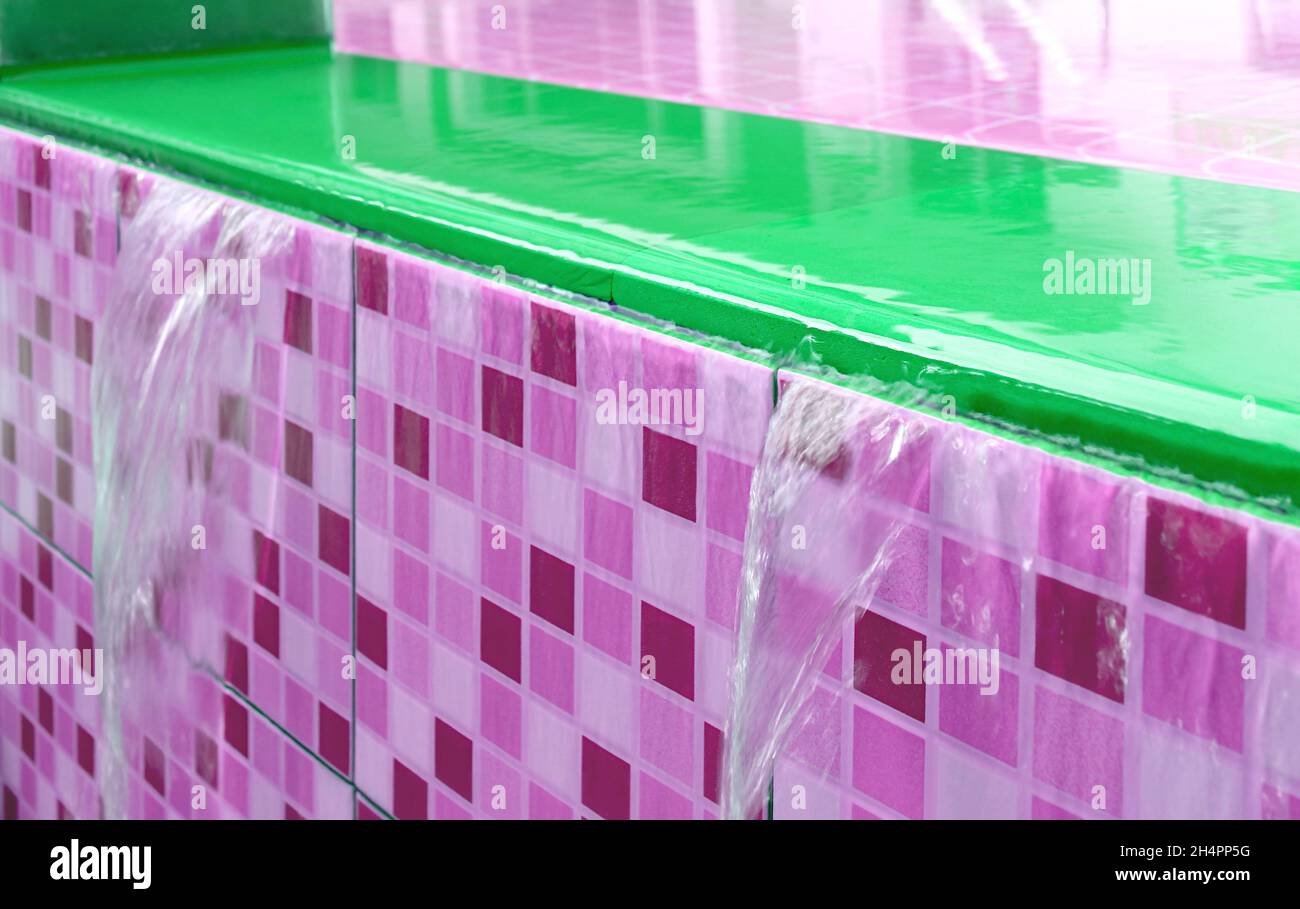 Closeup overflowing water of vibrant green and magenta pink tiled ...