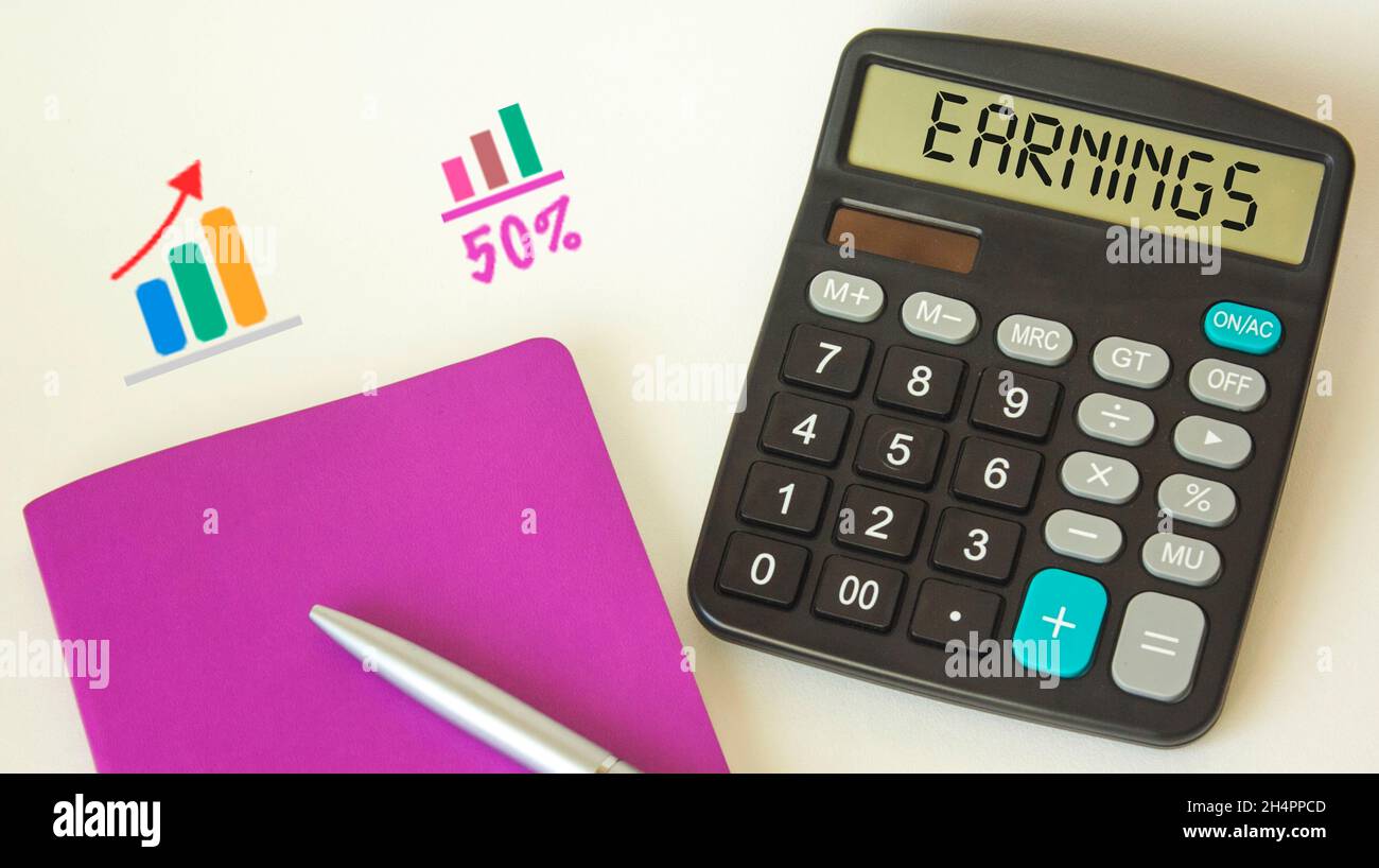 Earnings text word on calculator, charts and notepad on white ...