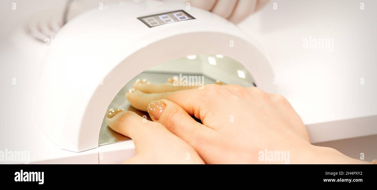 Female hand with manicured fingers dry inside UV light machine in ...