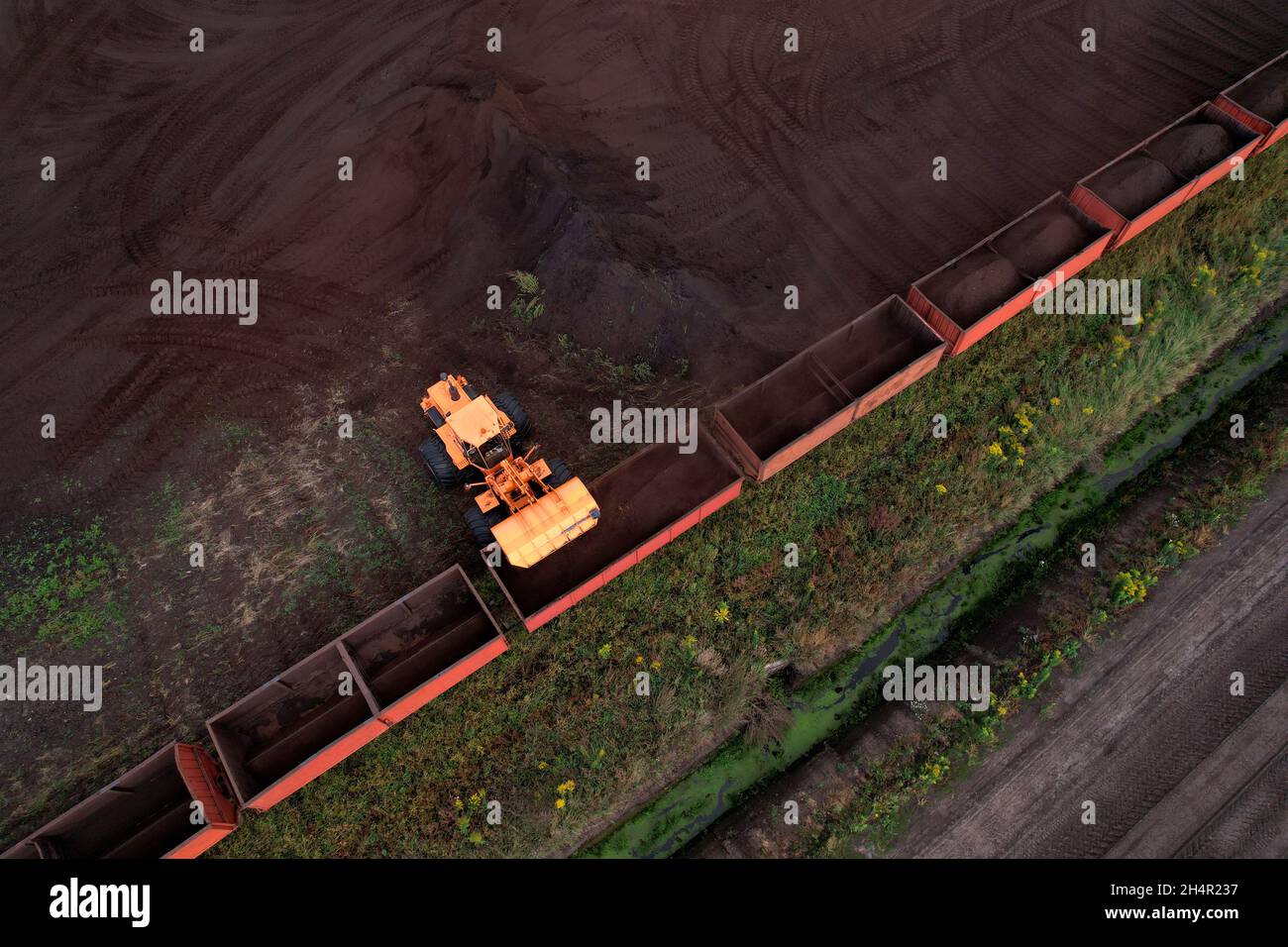 Wheel loader loads peat in freight cars. Aerial view of diesel ...
