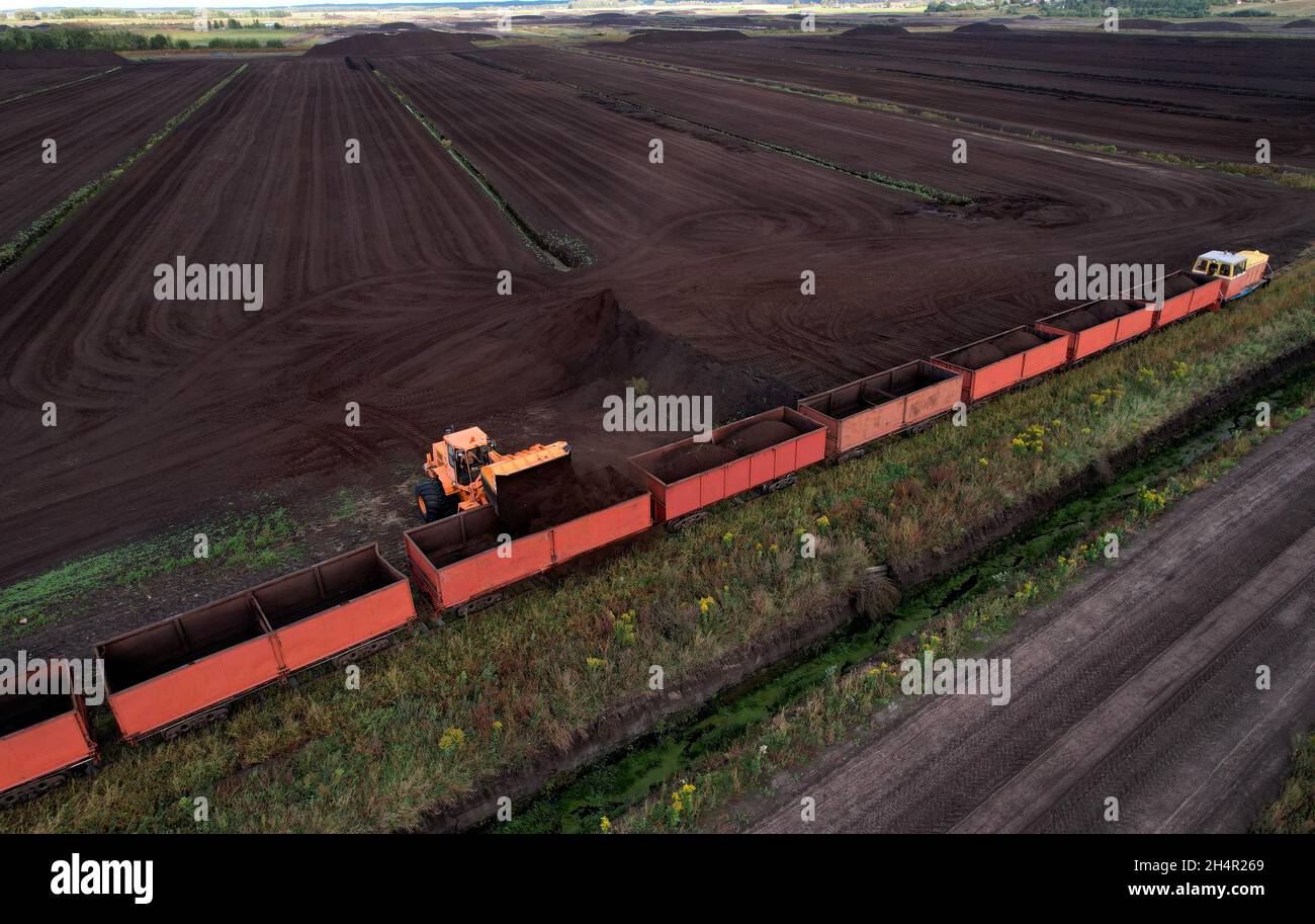 Wheel loader loads peat in freight cars. Aerial view of diesel ...