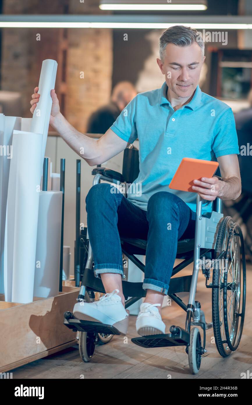 Man in wheelchair with tablet holding roll of paper Stock Photo - Alamy