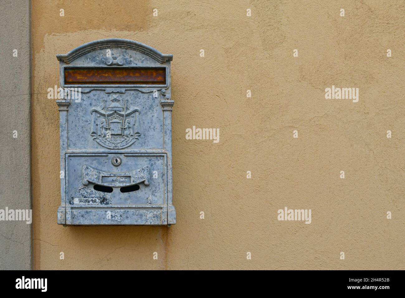 Close-up of a gray metal mailbox hanging on the wall of an old house ...