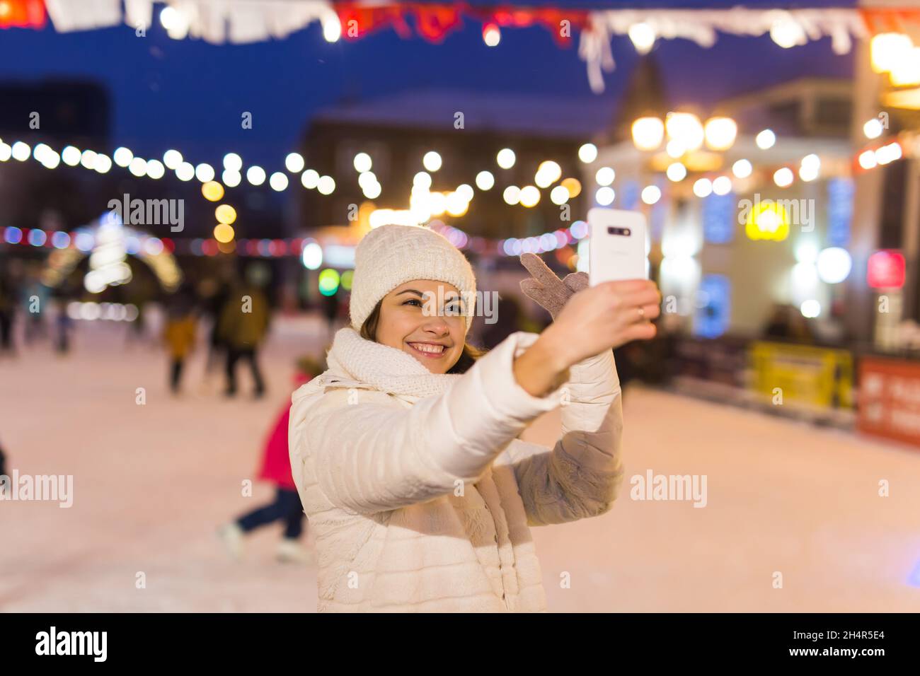 Happy young woman in winter on the ice rink taking picture on ...