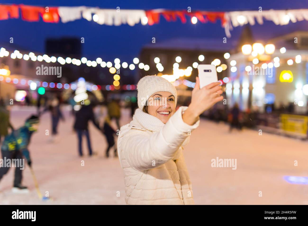 Happy young woman in winter on the ice rink taking picture on ...