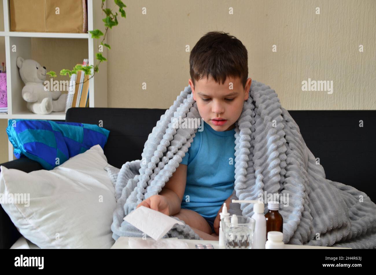 Sick child boy lying in bed with a fever, resting at home. a boy with a ...