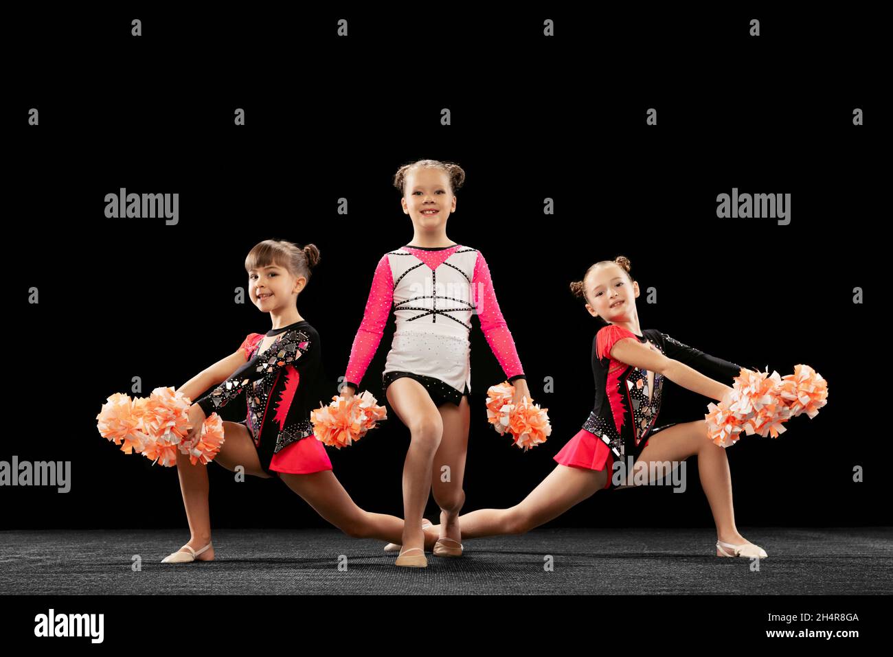 Full-length portrait of three girls, cheerleaders training in stage ...