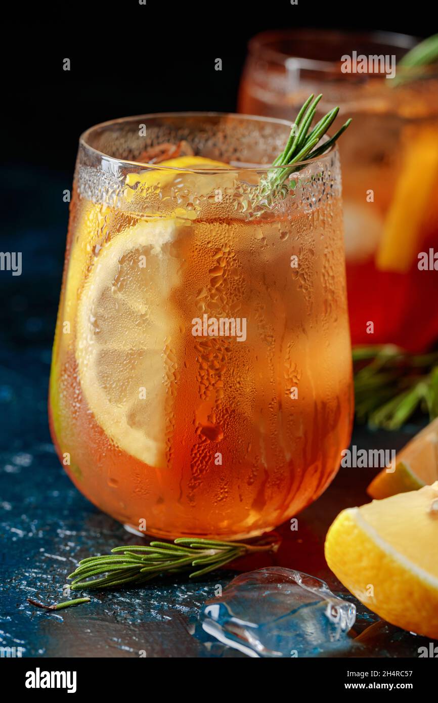 Traditional iced tea with lemon, rosemary, and ice on a dark blue table ...