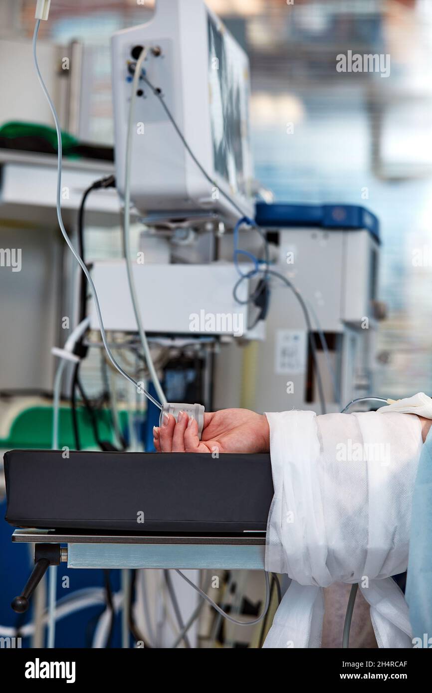 The patient's hand is under the IV with a pulse oximeter on the finger ...