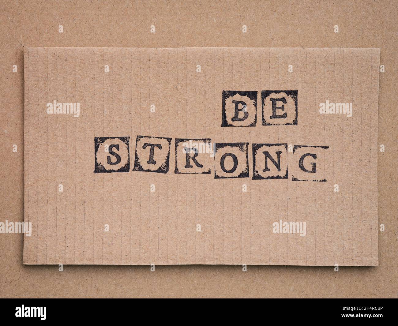 Cardboard with words Be Strong made by black alphabet stamps Stock ...