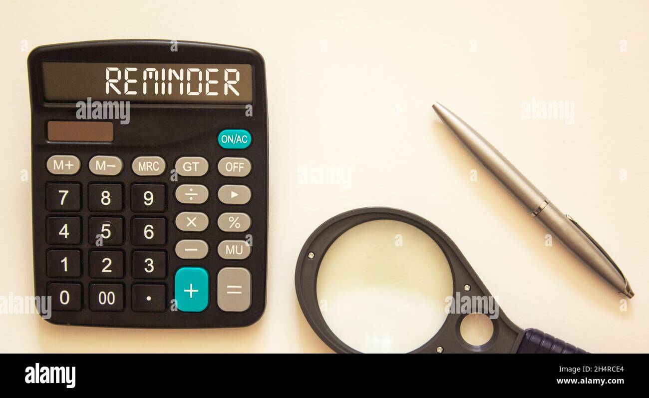 Reminder, the text is written on a calculator, a pen and a magnifying ...