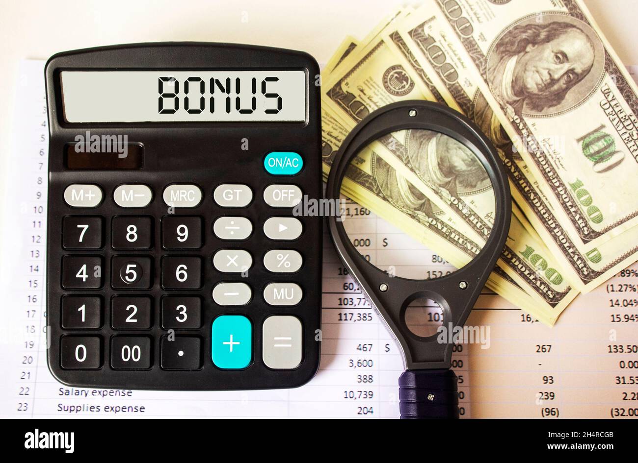 Calculator with text Bonus and paper money with magnifying glass on ...