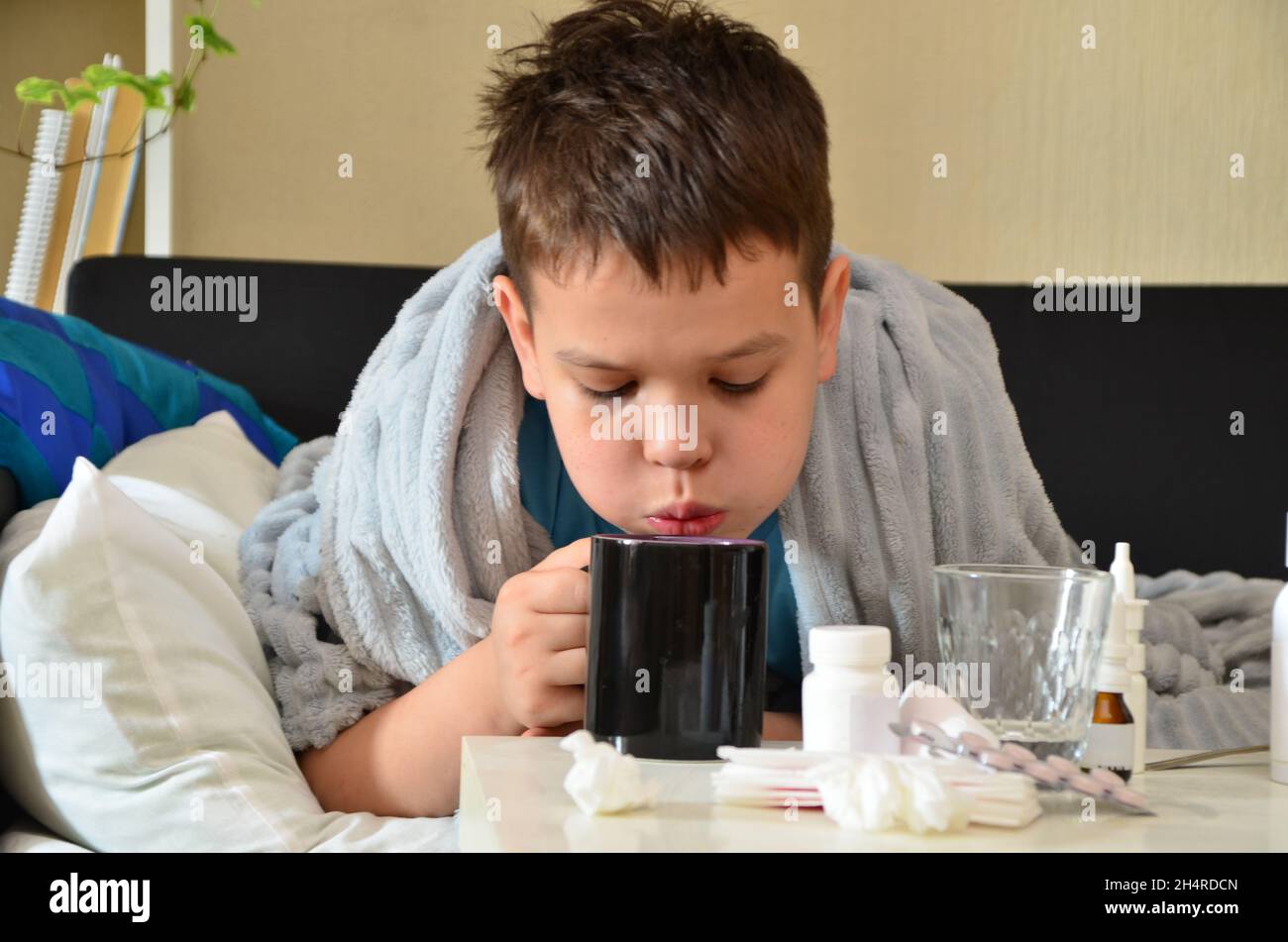 Sick child boy lying in bed with a fever, resting at home. a boy with a ...