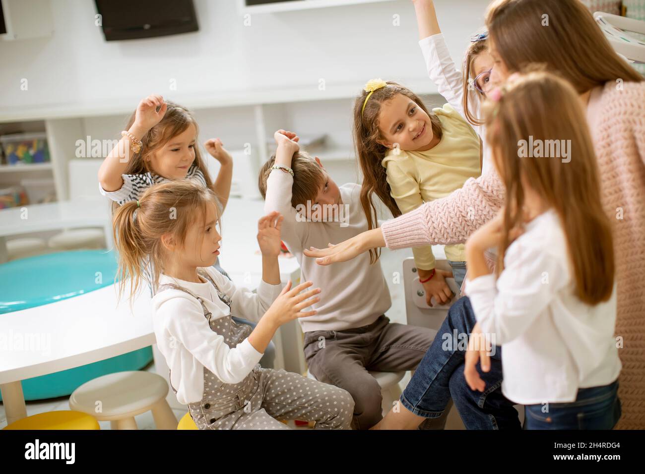 Group of cute preschool kids put hands together with their nursery ...