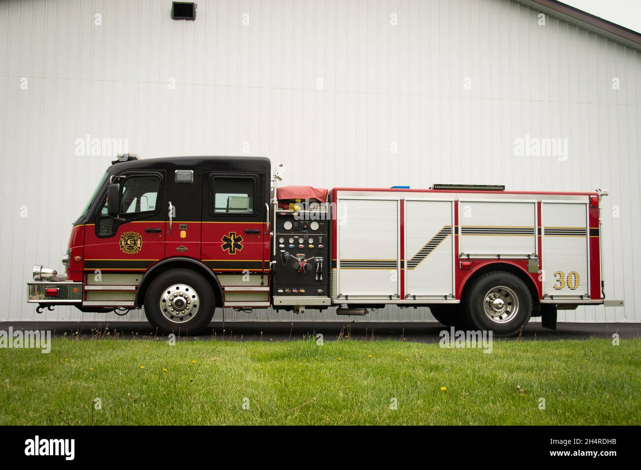 Firetruck parked on a lawn against a wall of a building Stock Photo - Alamy