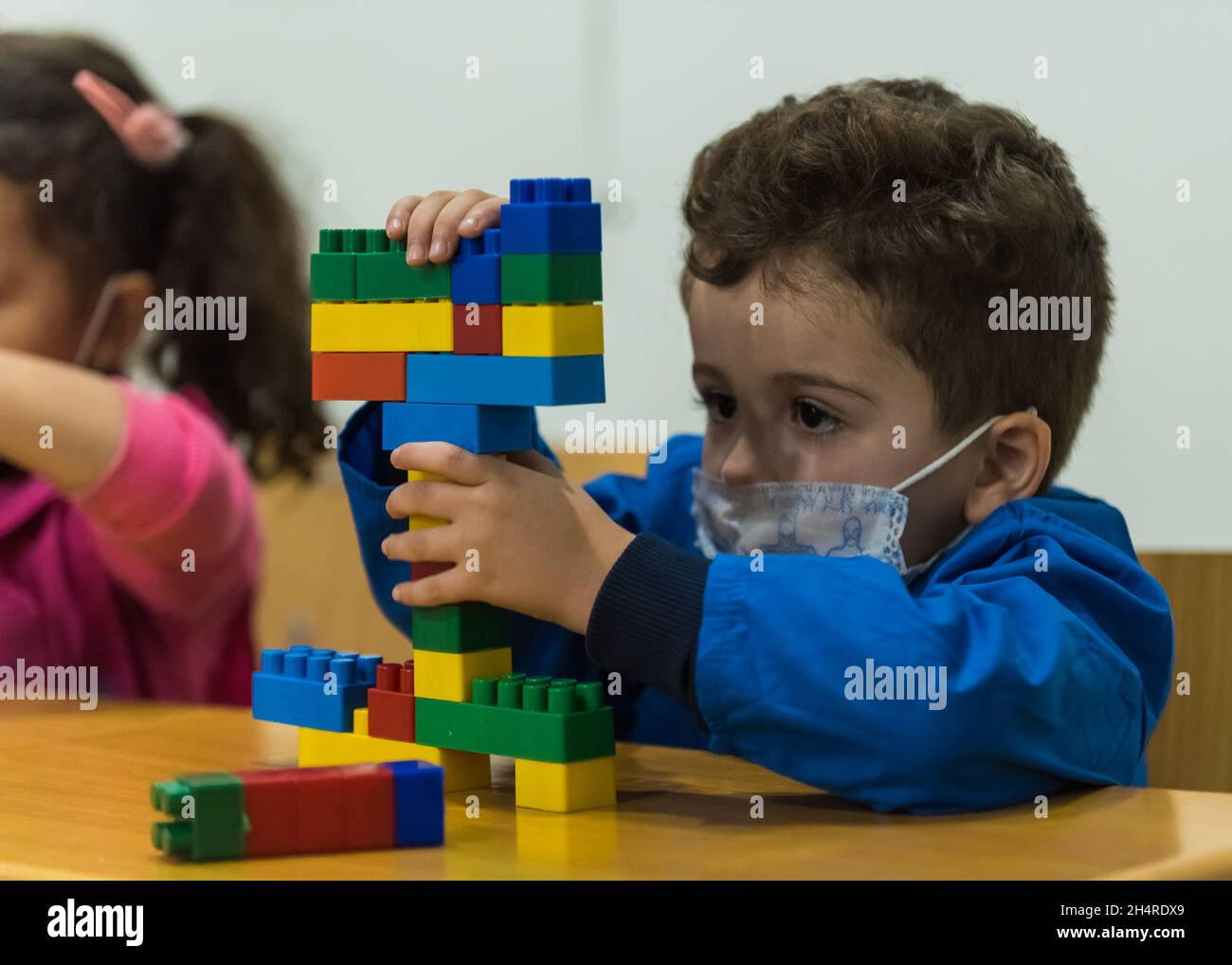 Portrait of little children playing colorful blocks in classroom ...