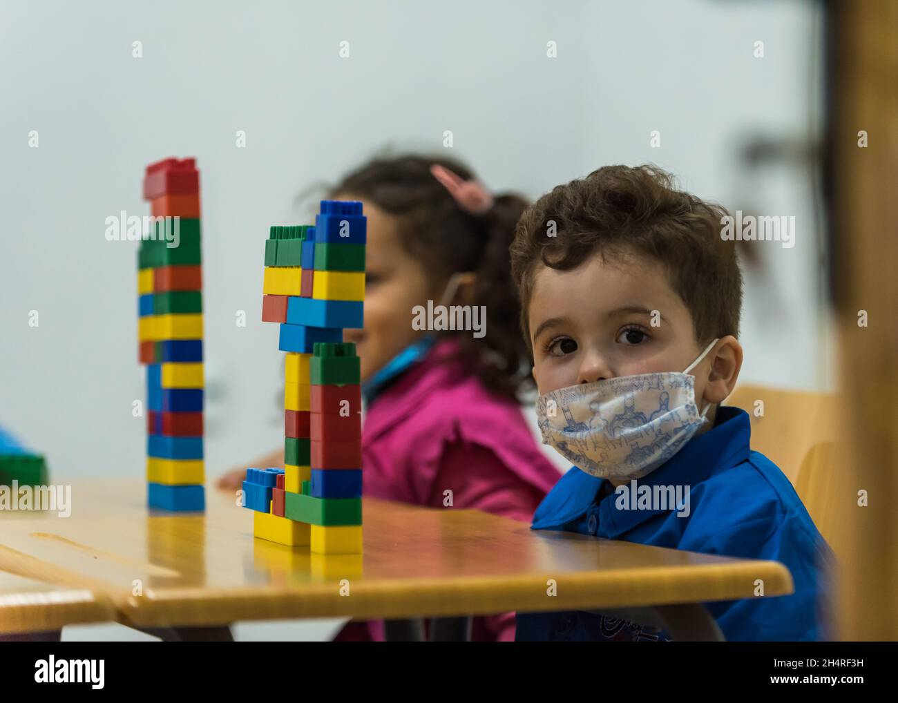 Portrait of little children playing colorful blocks in classroom ...